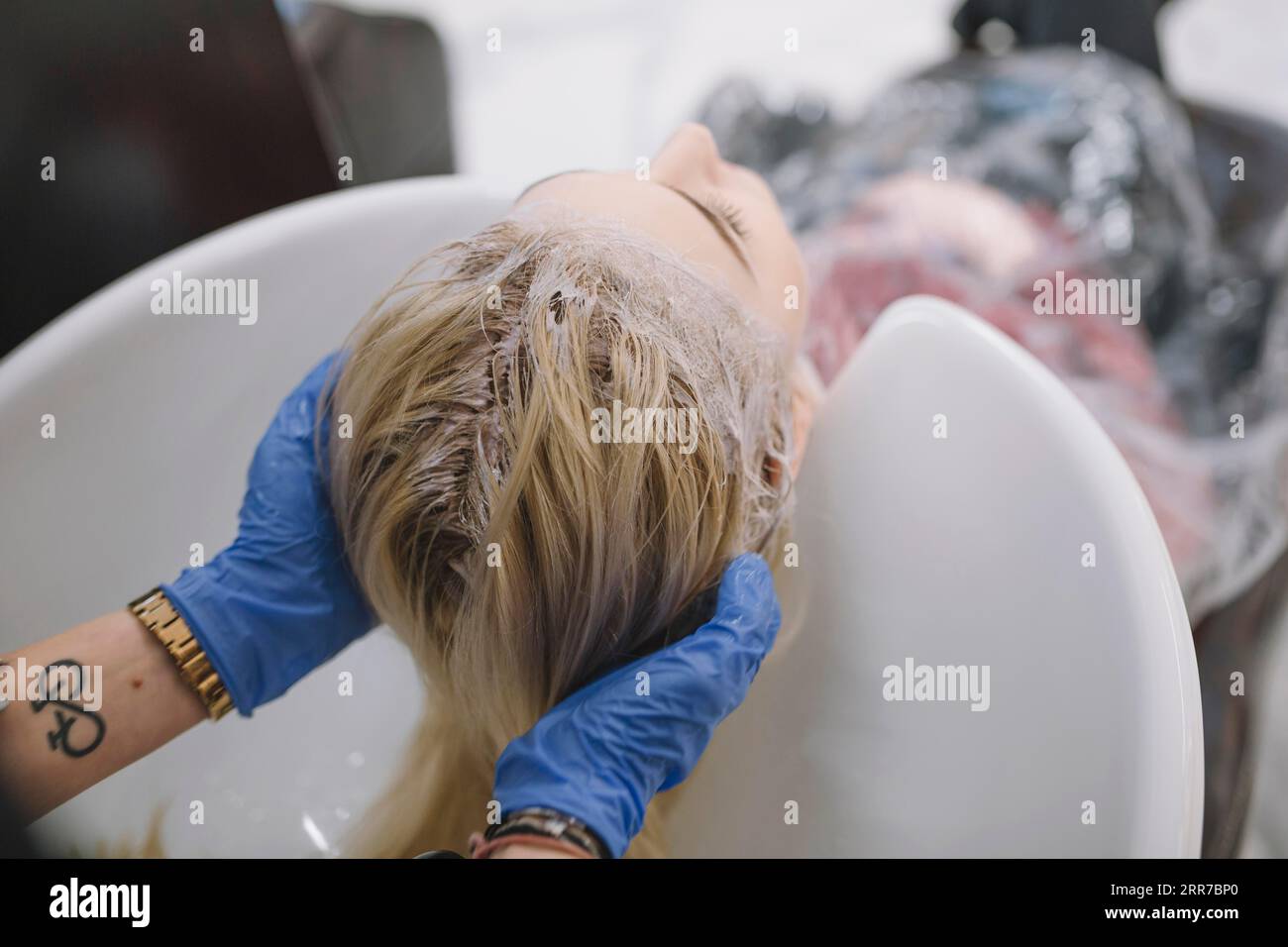 Stylist washing off dye sink Stock Photo - Alamy
