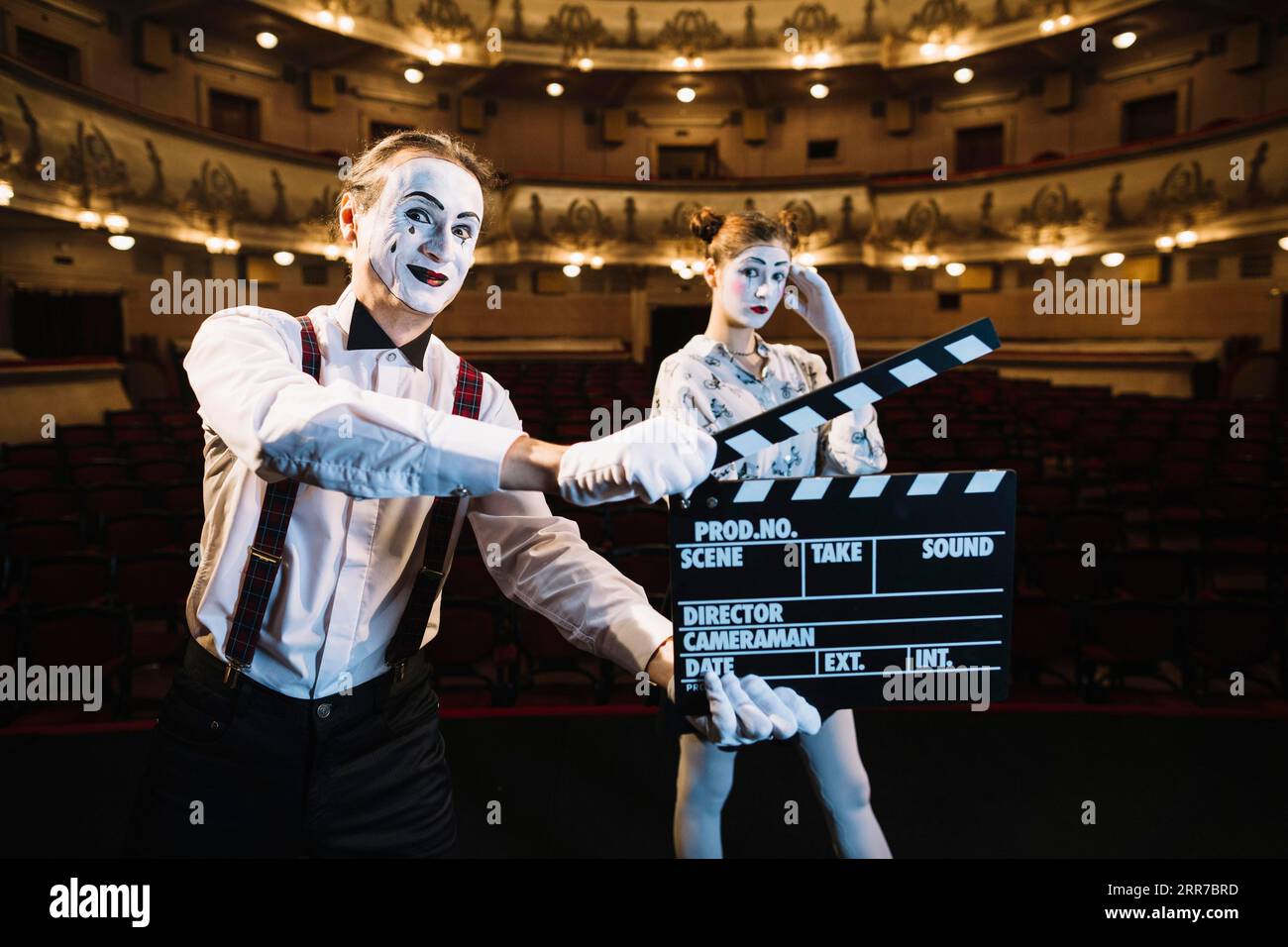 Smiling male mime artist holding clapperboard front female mime stage ...