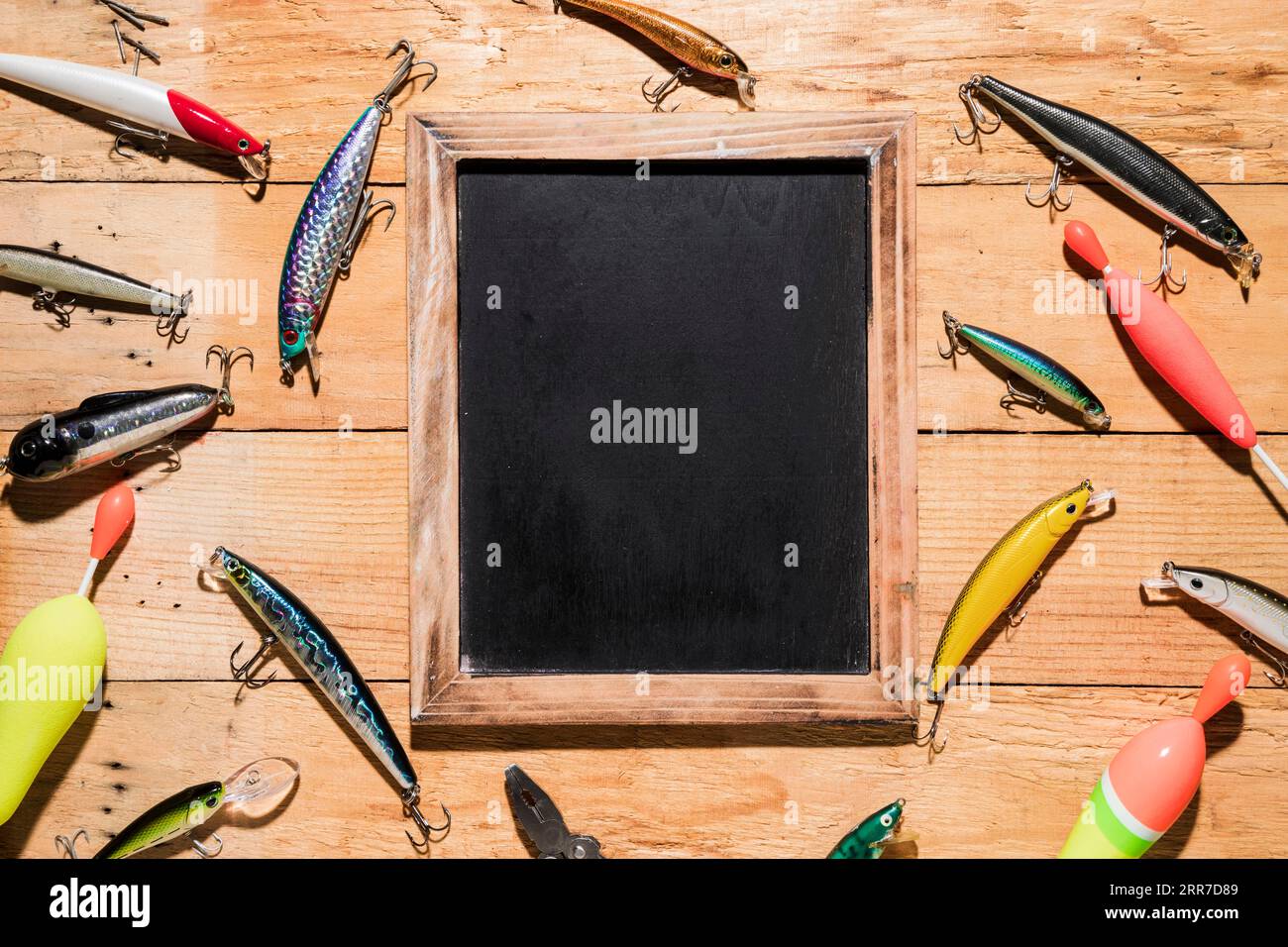 Different type fishing lures around black wooden slate wooden backdrop ...