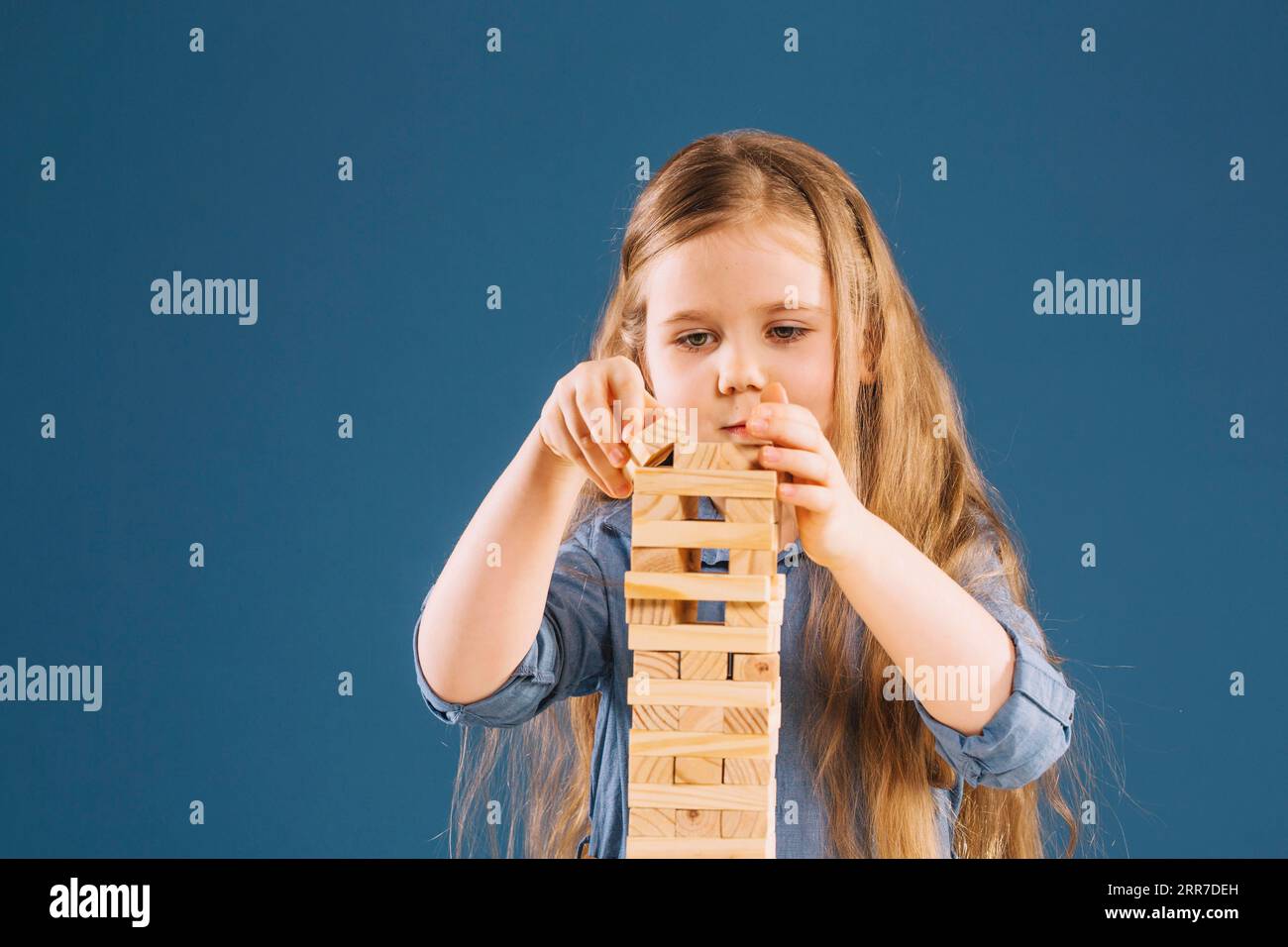 Focused girl building jenga tower Stock Photo - Alamy