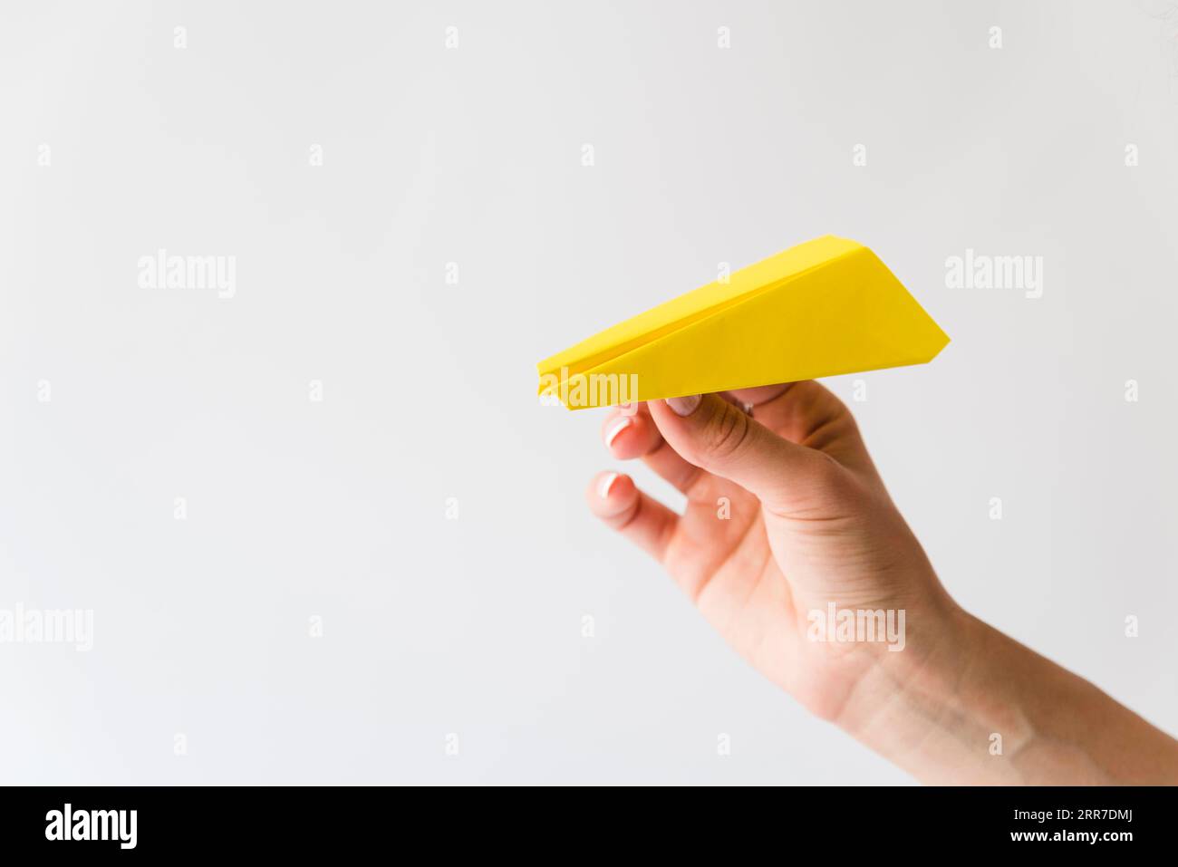 Hand holding yellow paper plane Stock Photo - Alamy