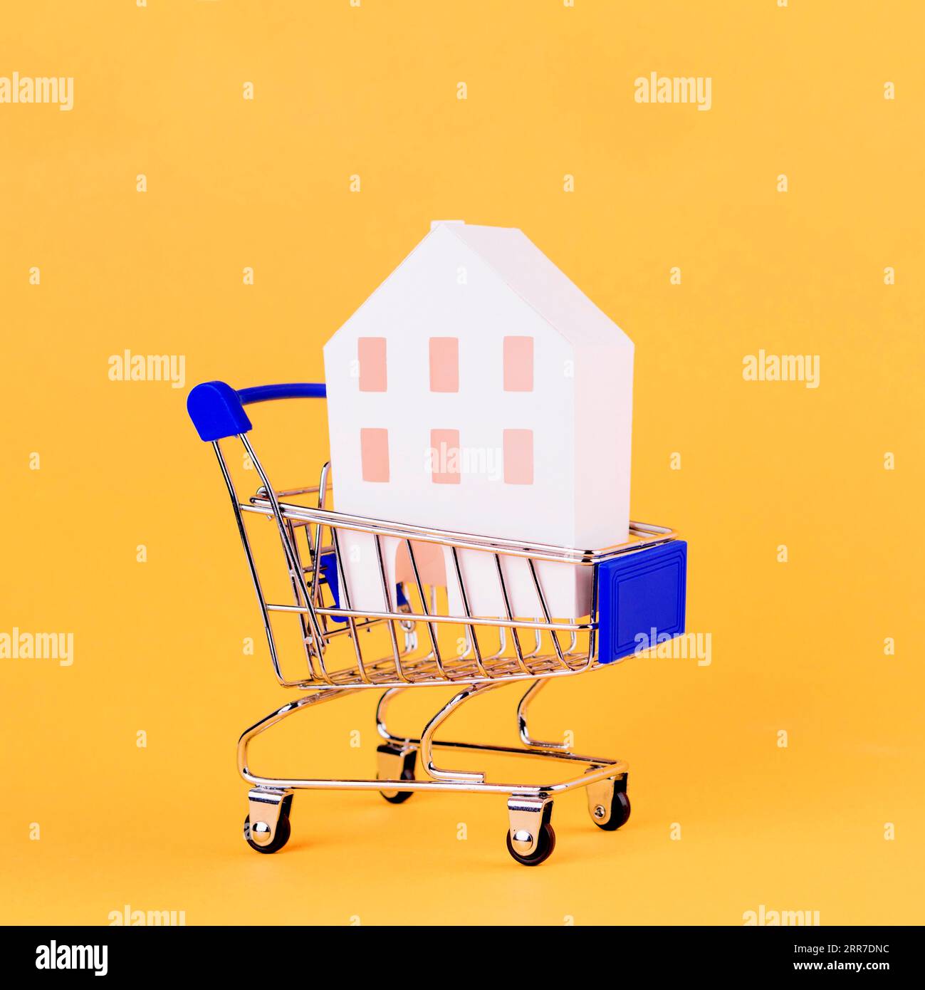 House model inside shopping cart against yellow backdrop Stock Photo ...