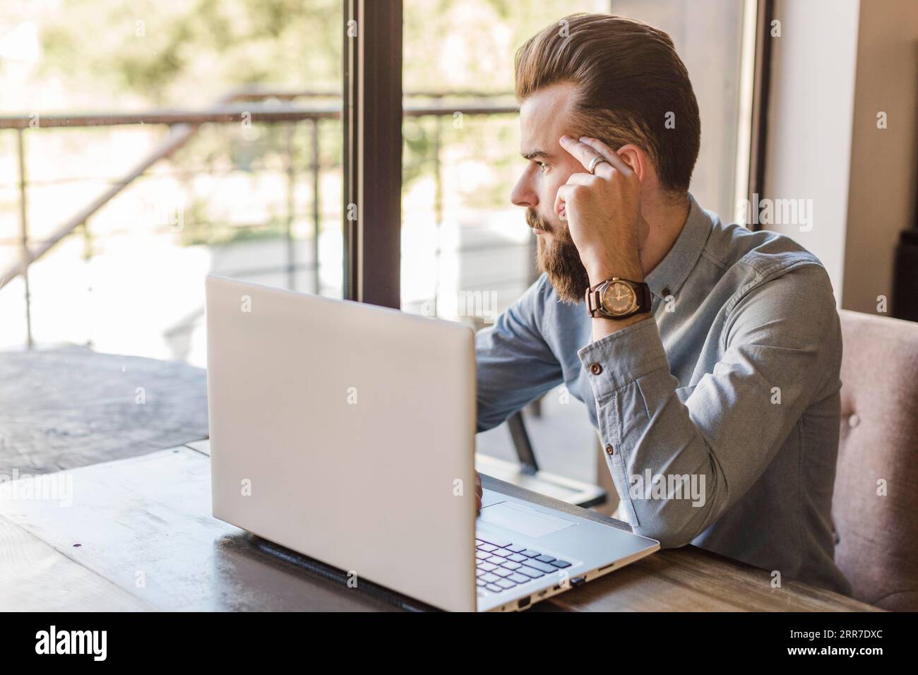 Man looking outside window with laptop desk caf Stock Photo - Alamy