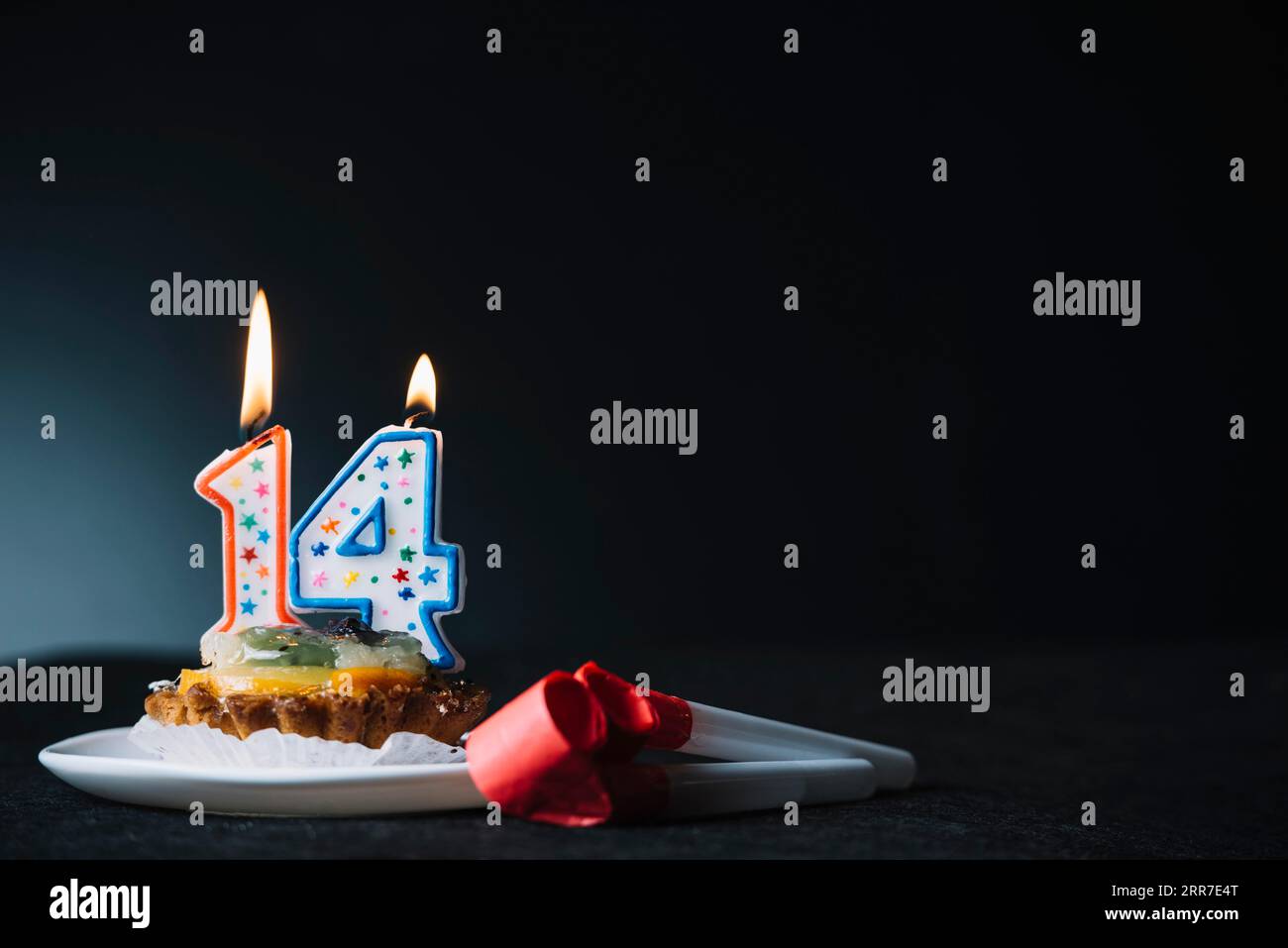 Number 14 birthday lighted candle slice tart party horn blower against ...