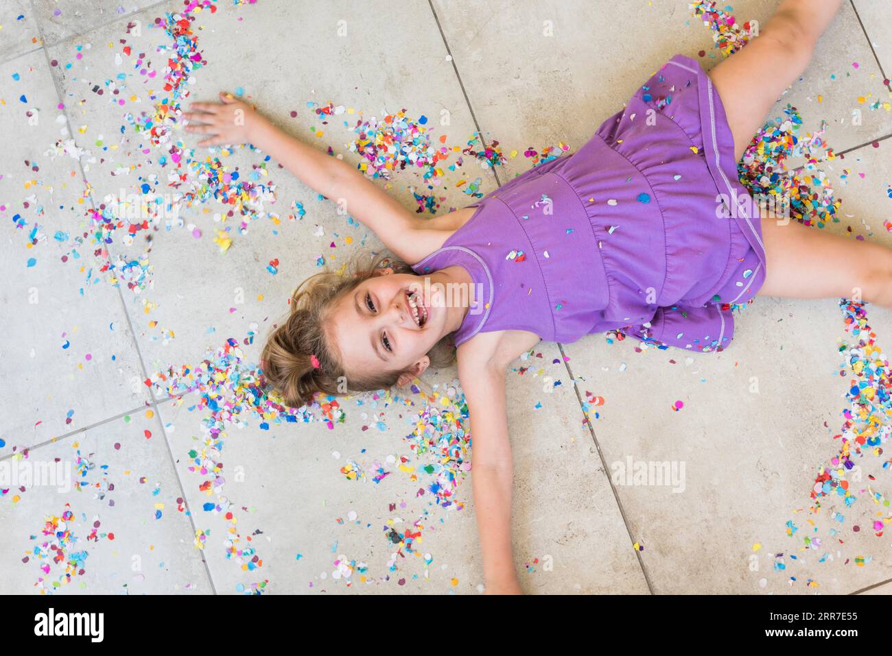 Overhead view happy cute girl lying with confetti floor Stock Photo - Alamy