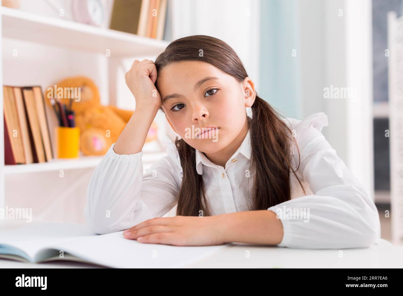 Tired schoolgirl doing homework desk Stock Photo - Alamy