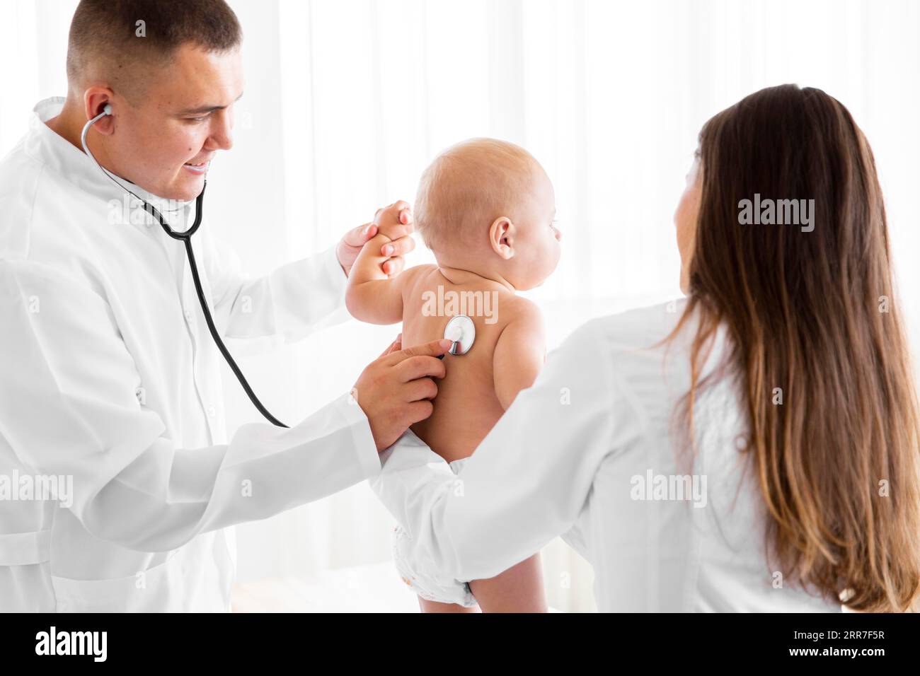 Back view doctors holding new born baby Stock Photo - Alamy