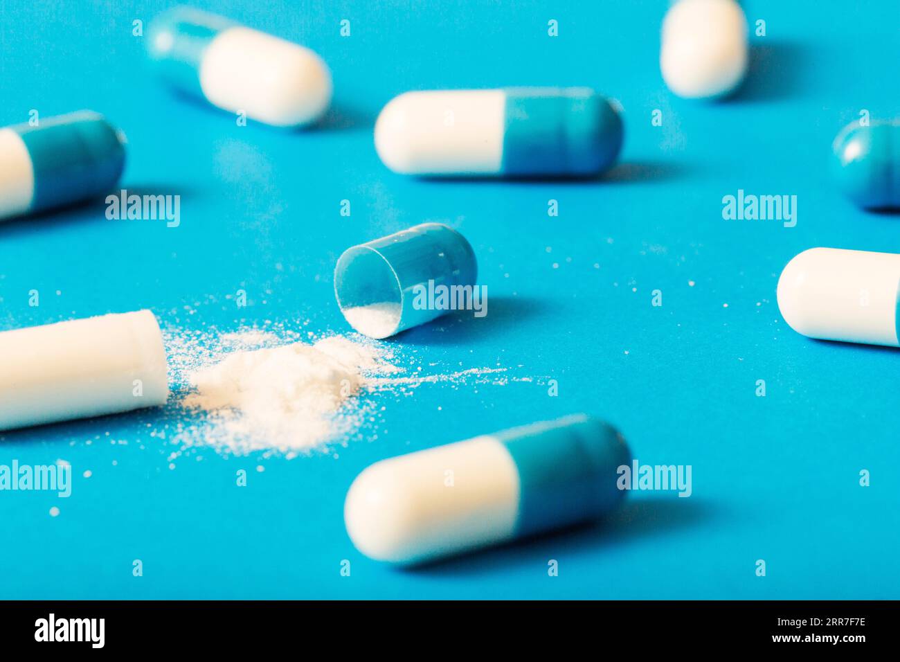 Broken capsule with white powder blue background Stock Photo - Alamy