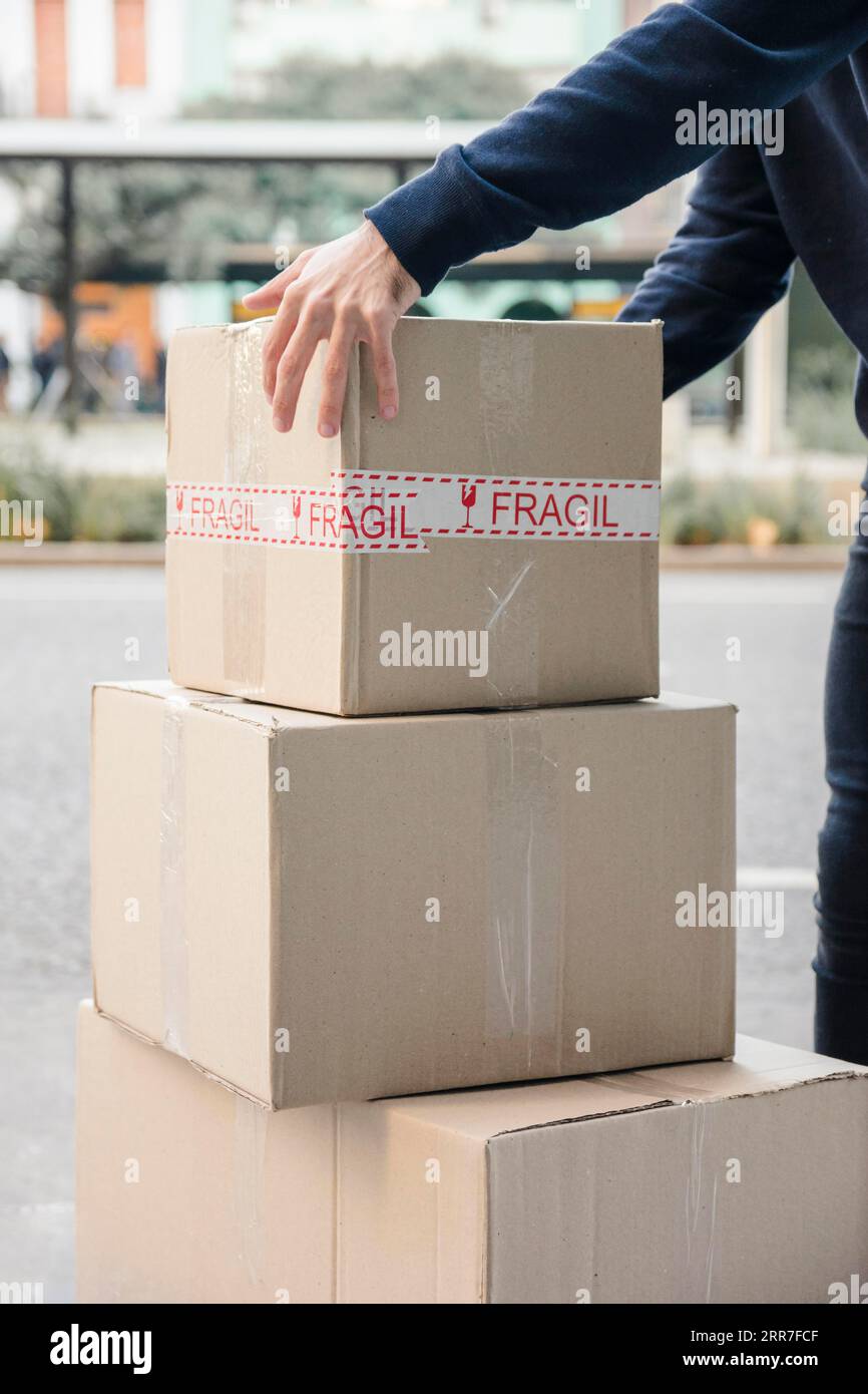 Close up delivery man s hand picking up cardboard box Stock Photo - Alamy