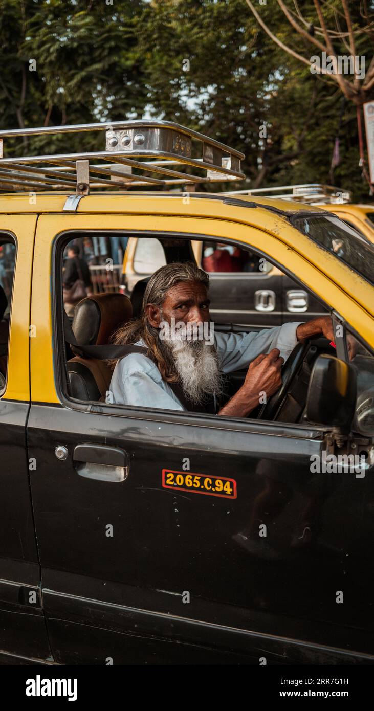 Old male Indian taxi driver sitting in his cab, stuck in traffic in ...