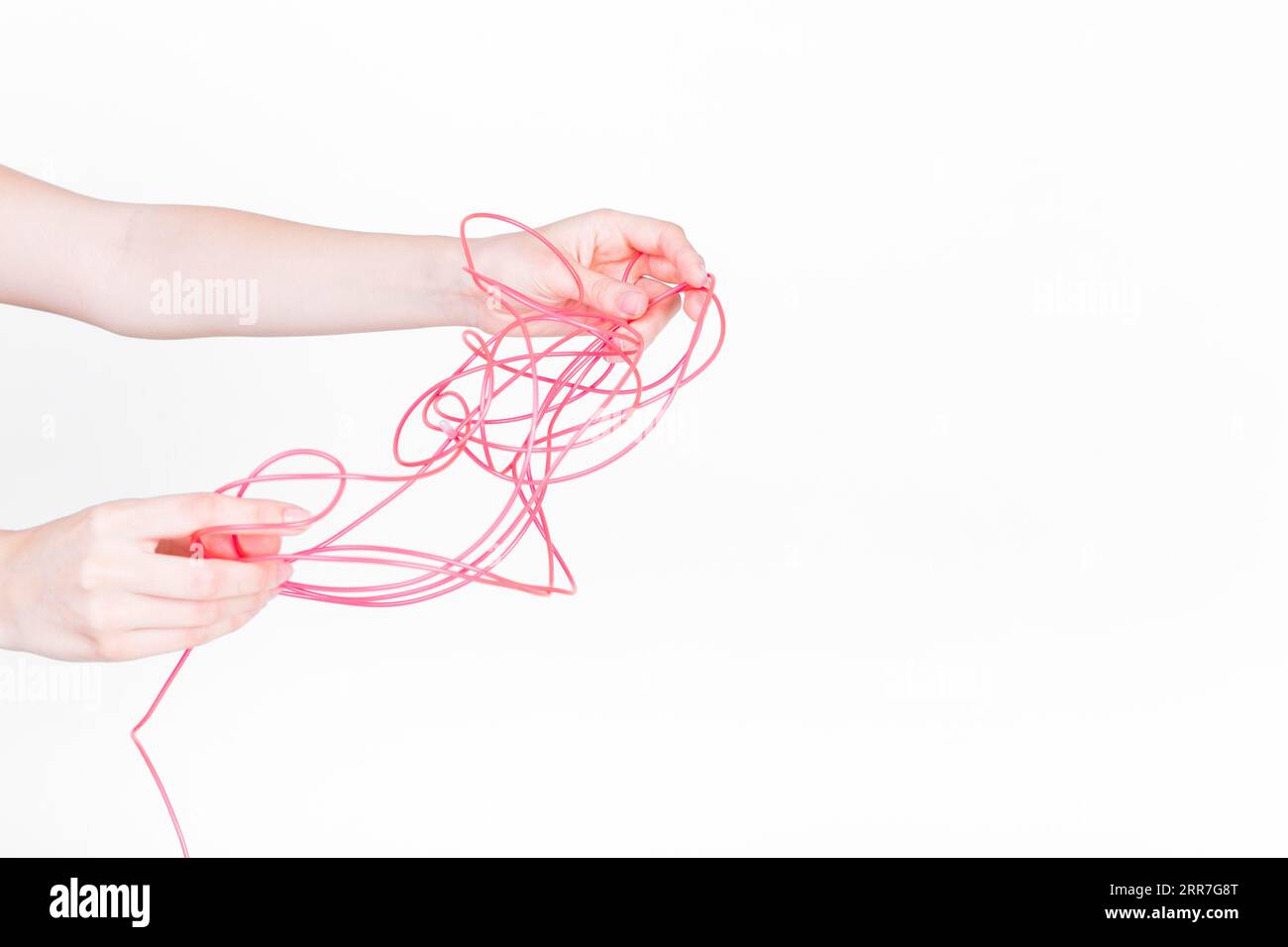 Human hand trying untangle red wire white background Stock Photo - Alamy