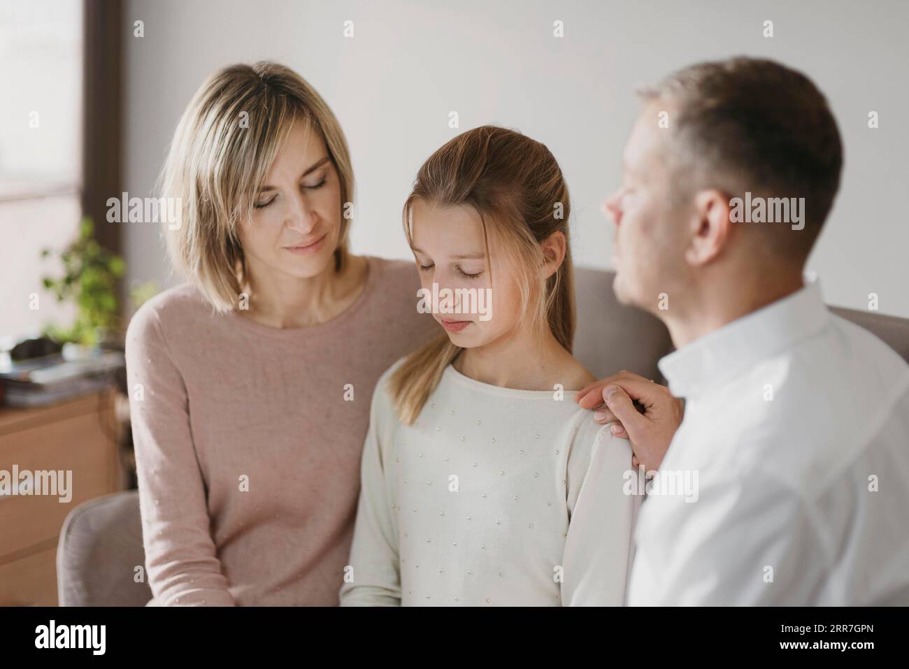 Parents daughter praying together Stock Photo - Alamy