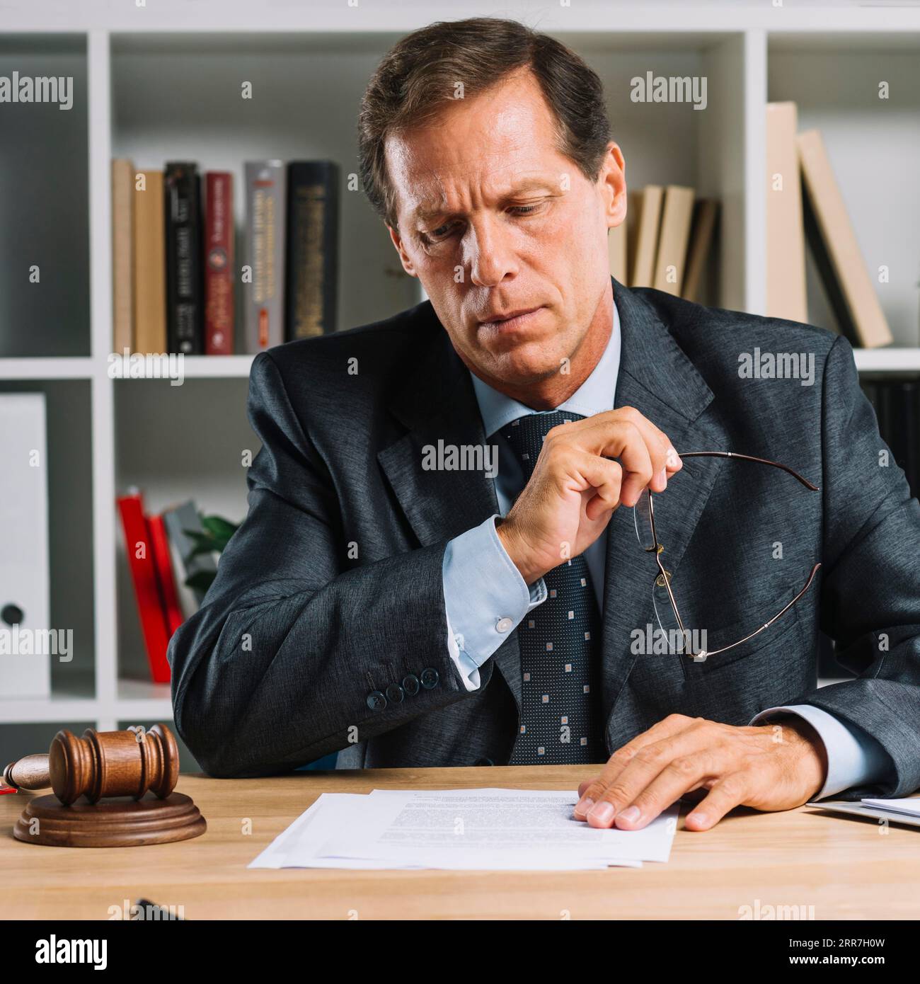 Serious mature lawyer reading document desk courtroom Stock Photo - Alamy