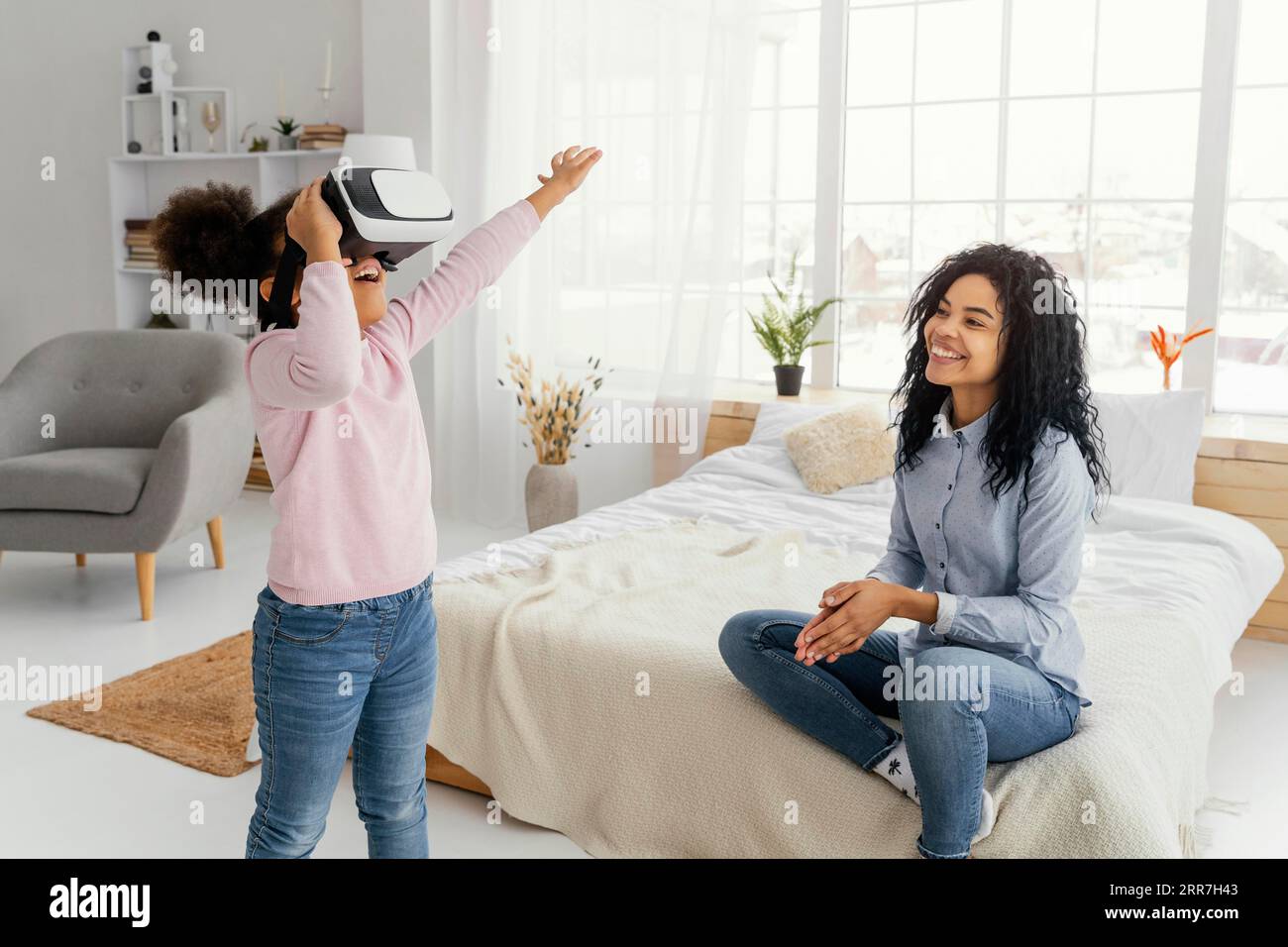 Smiley mother watching daughter play with virtual reality headset Stock ...