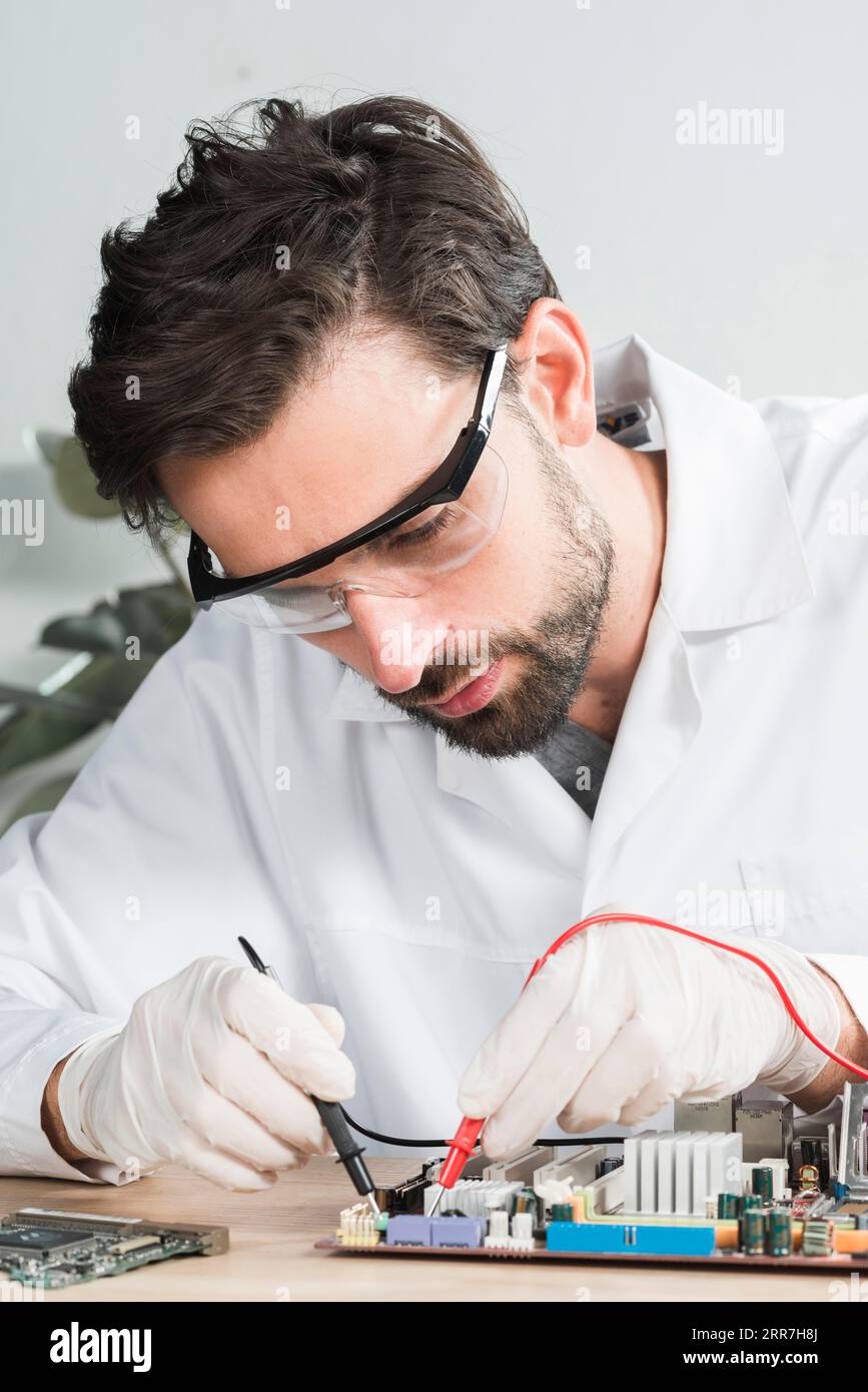 Technician examining computer motherboard with digital multimeter Stock ...