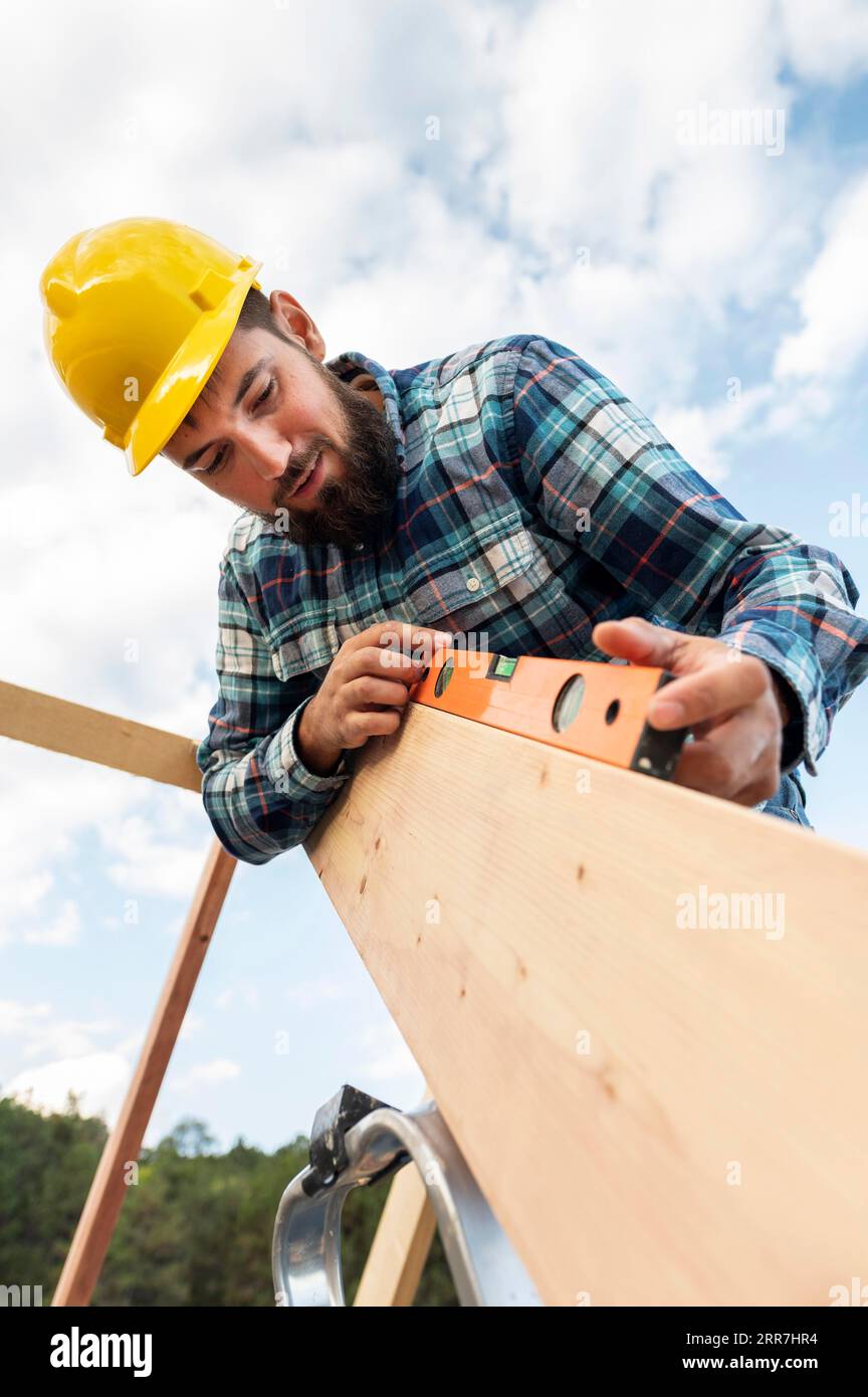 Worker with hard hat level checking roof timber Stock Photo - Alamy