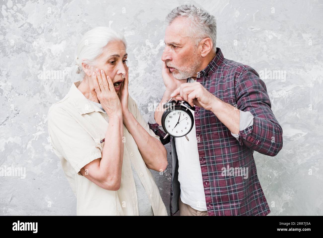 Elder couple holding clock Stock Photo - Alamy