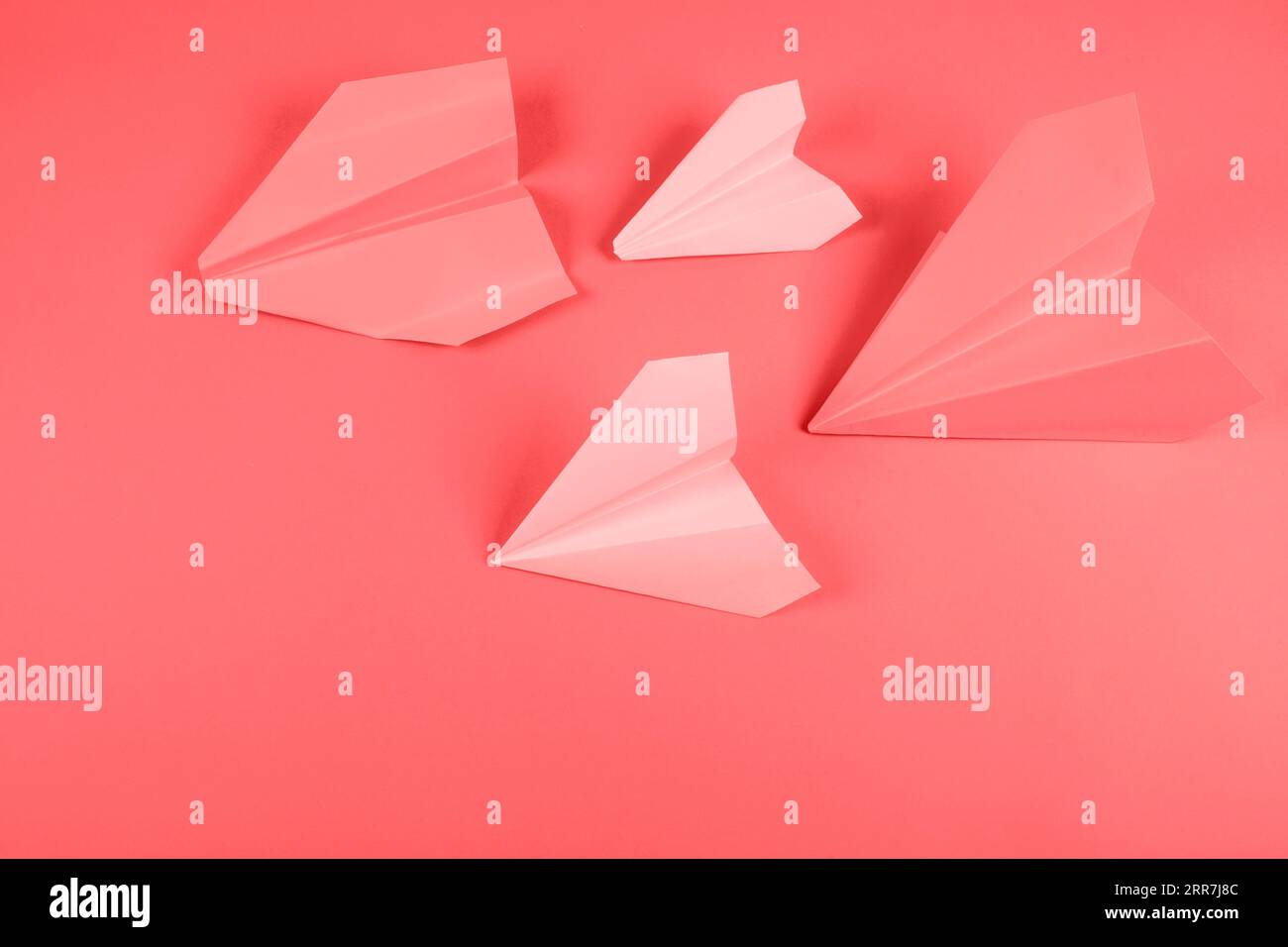 Coral pink paper airplane colored background Stock Photo - Alamy