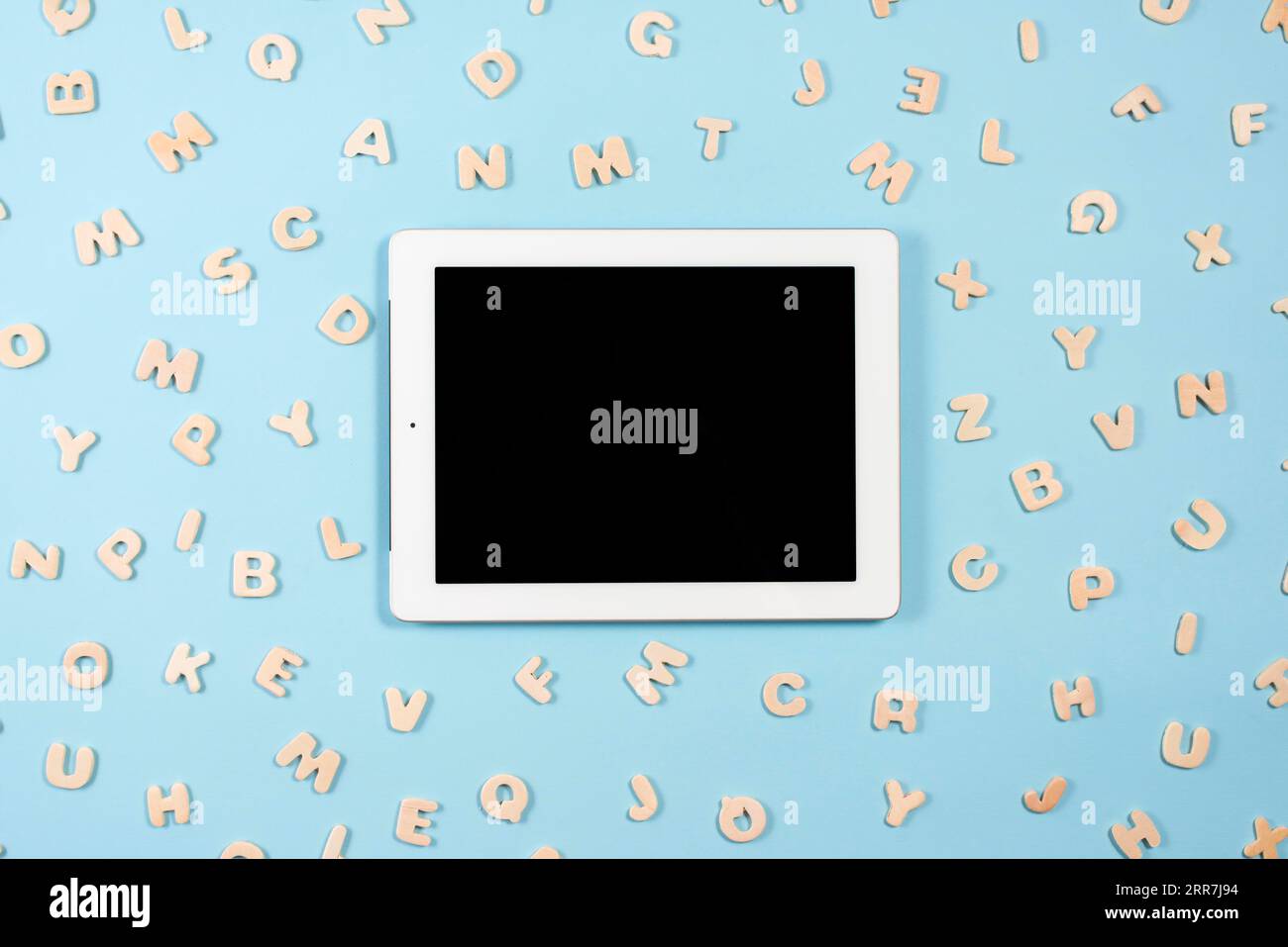 Digital tablet with black screen display surrounded with wooden letters ...