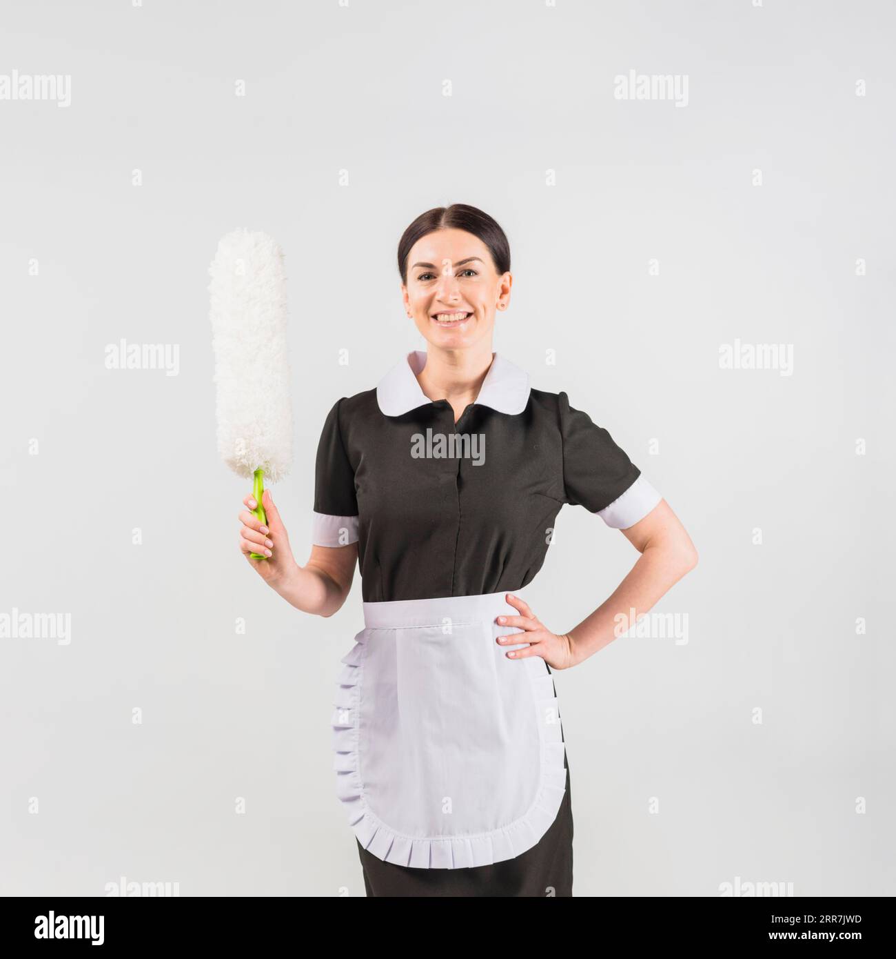 Maid with duster smiling Stock Photo - Alamy