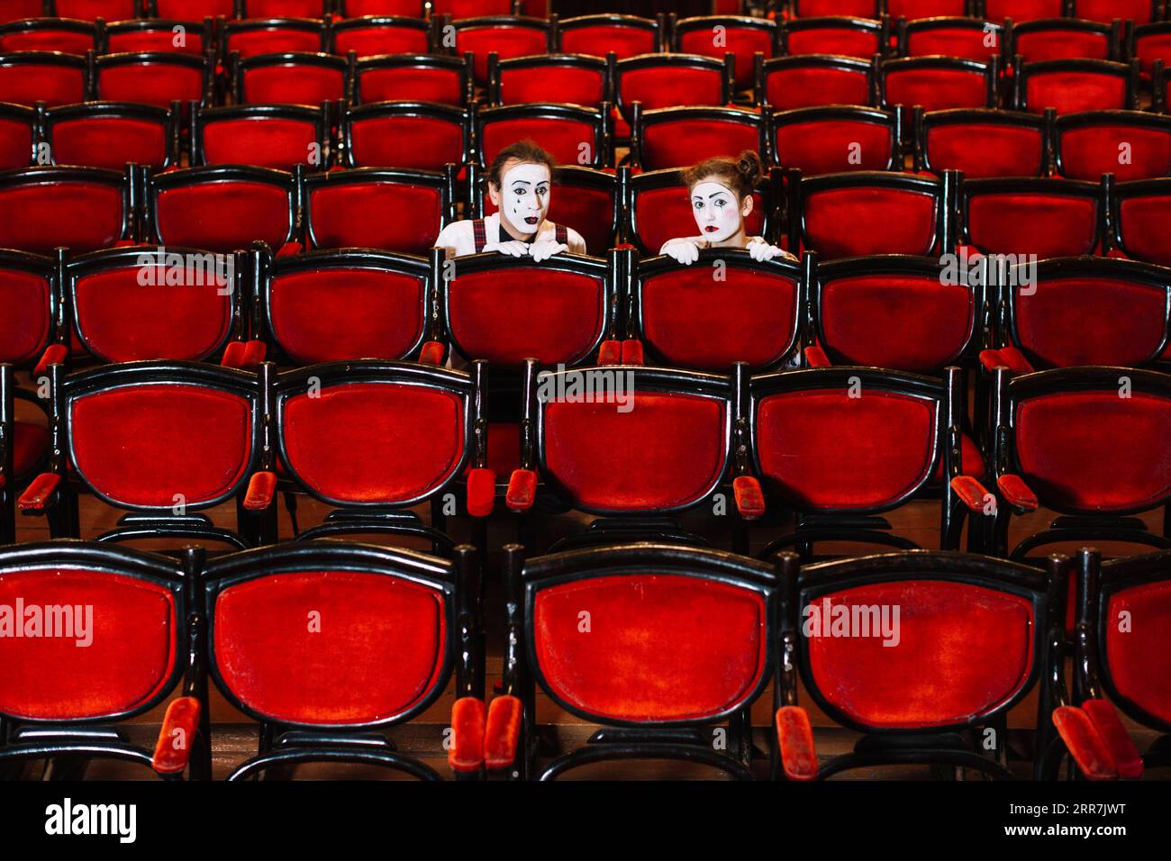 Male female mime artist hiding row arm chairs Stock Photo - Alamy