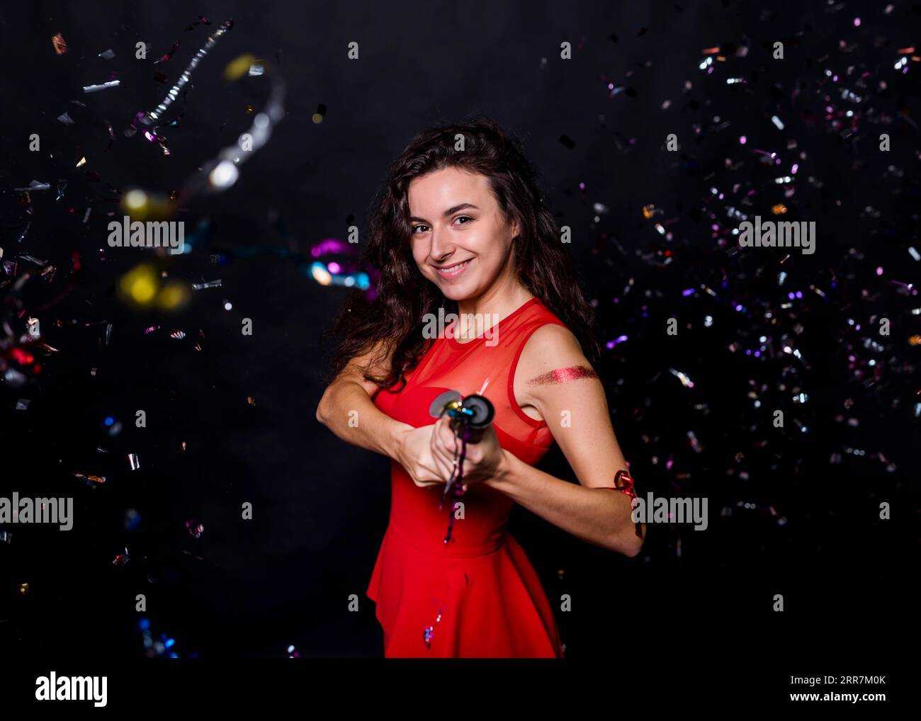 Young smiling woman with popper tossing confetti Stock Photo - Alamy