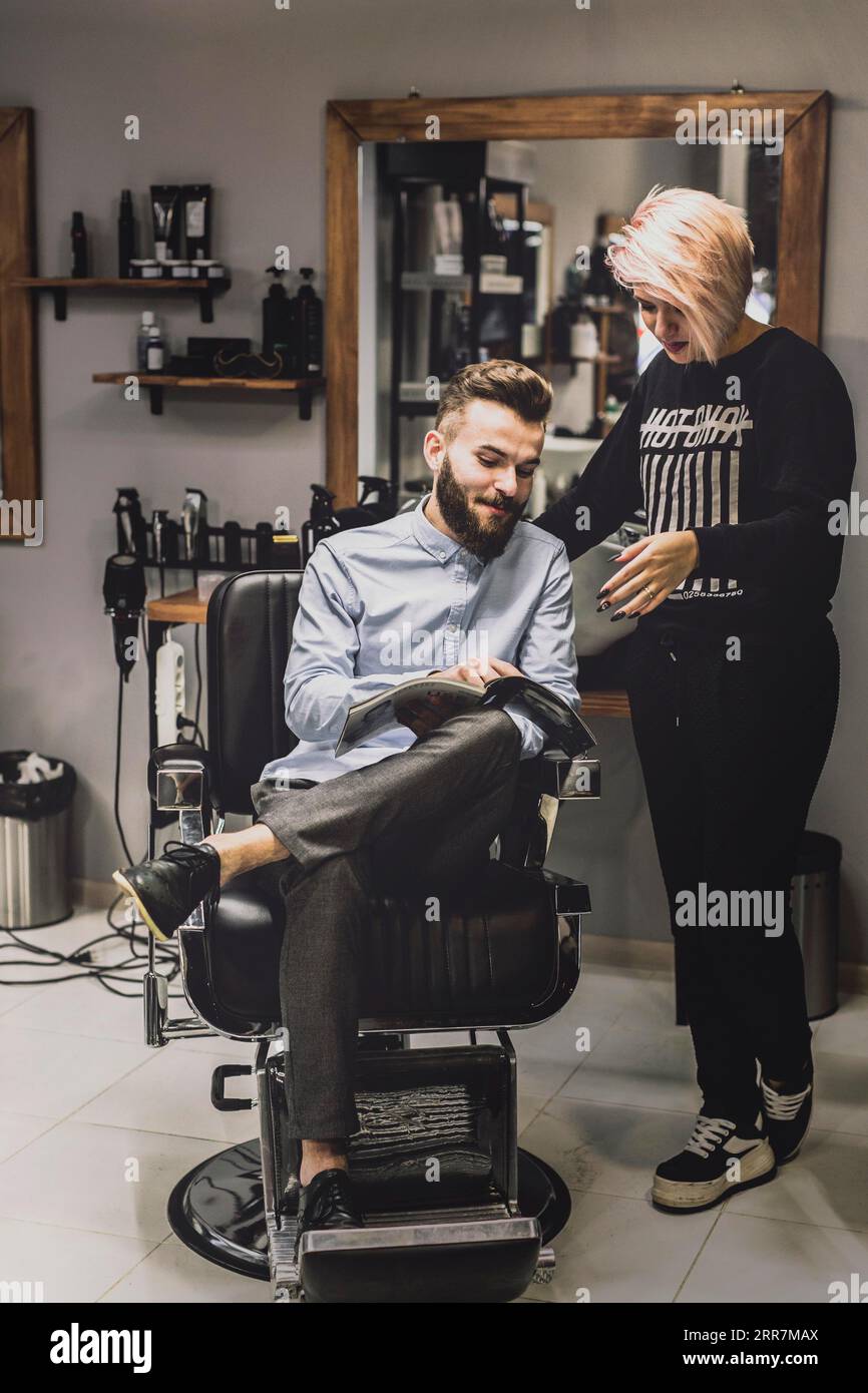 Customer showing magazine barber Stock Photo - Alamy