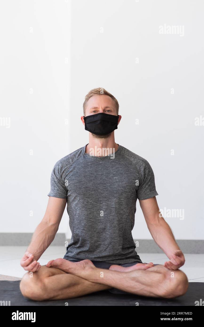 Full shot man with face mask doing sukhasana pose inside mat Stock ...