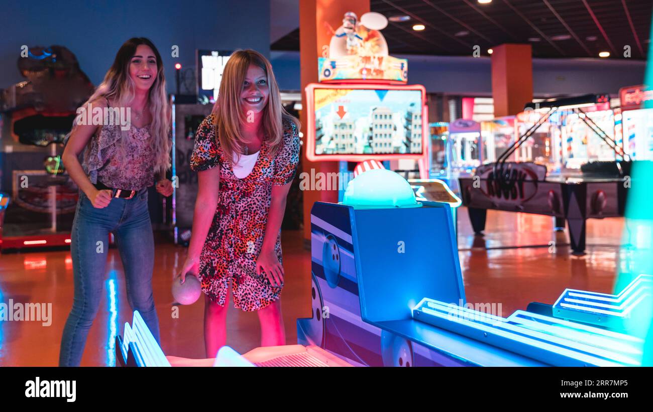 Happy women playing arcade game Stock Photo - Alamy