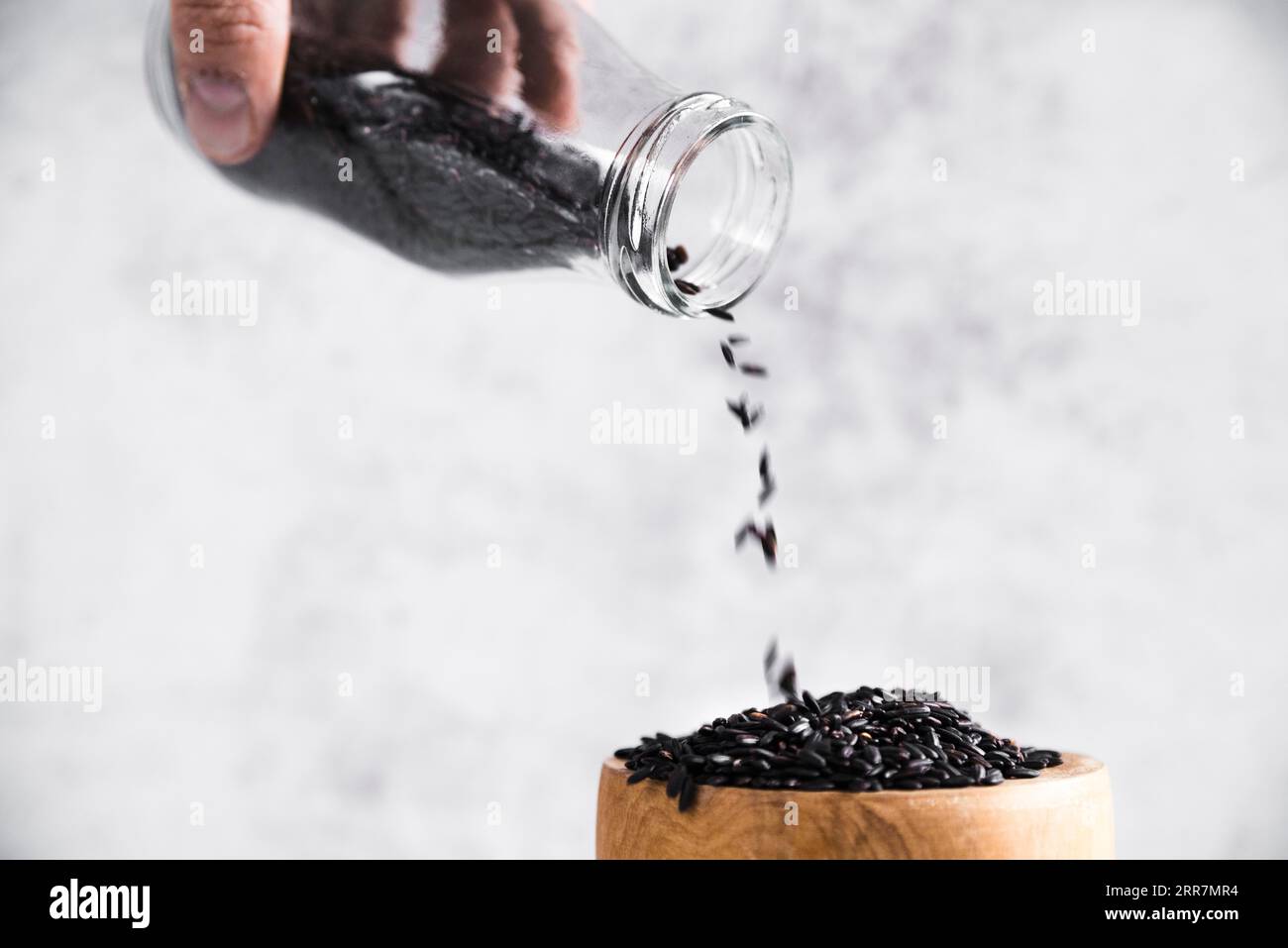 Hand holding bottle with black rice near bowl Stock Photo - Alamy