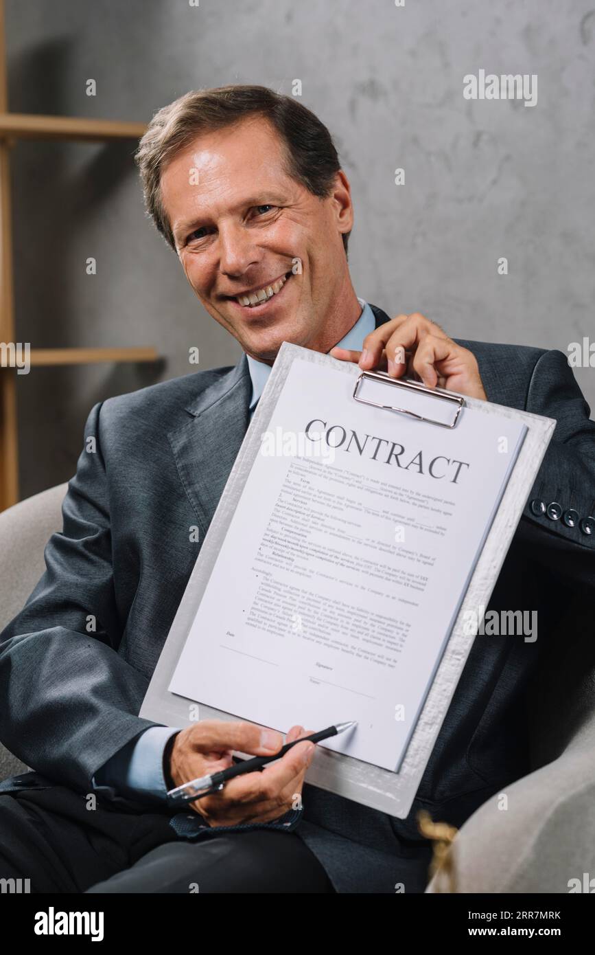 Happy mature lawyer pointing signature place contract document with pen ...