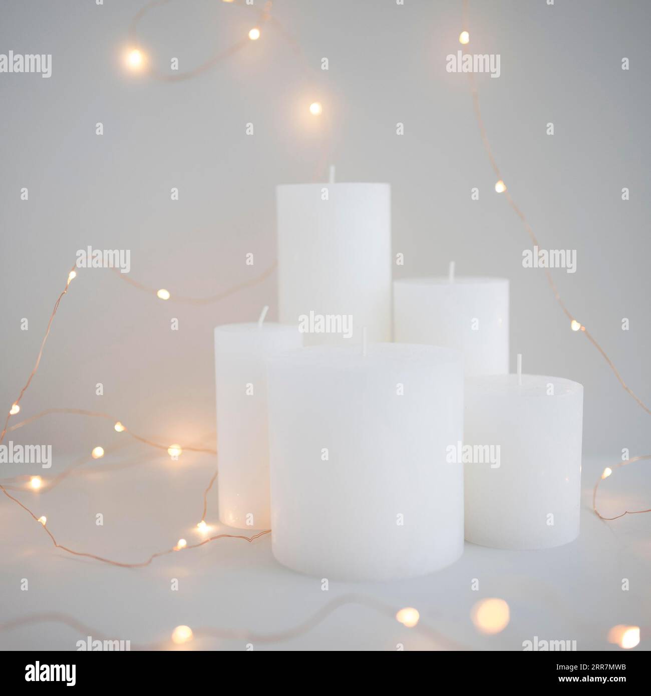 Illuminated fairy lights around white candles grey background Stock ...