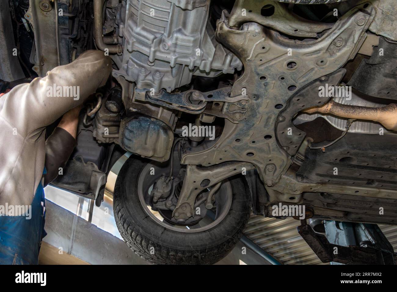 Car on a lift in a service station, an auto mechanic maintains the ...