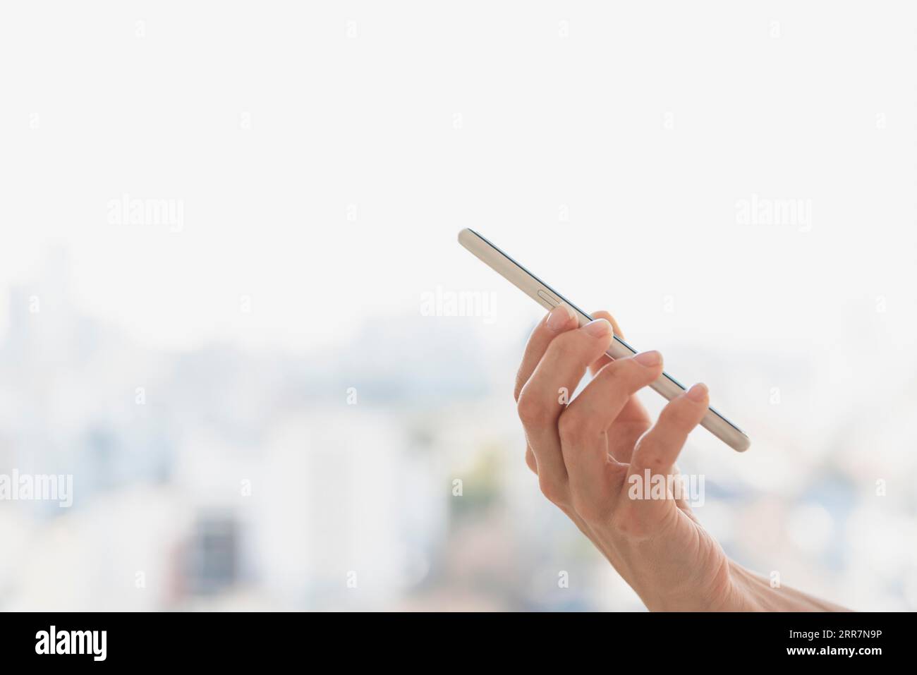 Side view hand holding phone with defocused background Stock Photo - Alamy