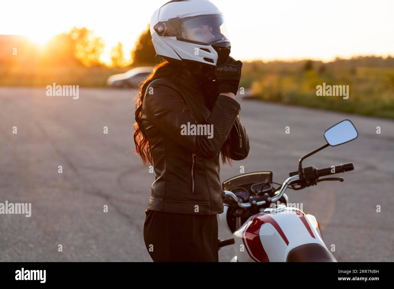 Side view woman taking off her helmet motorcycle Stock Photo - Alamy