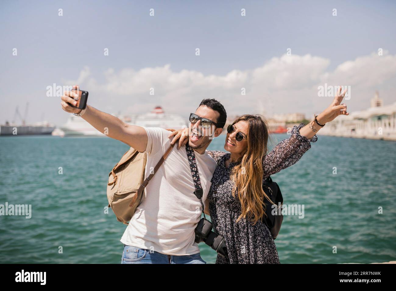 Woman making peace sign with her boyfriend taking selfie mobile Stock ...