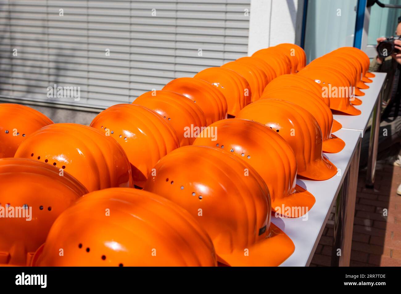 Orange-coloured safety helmets are on display for a factory tour Stock ...