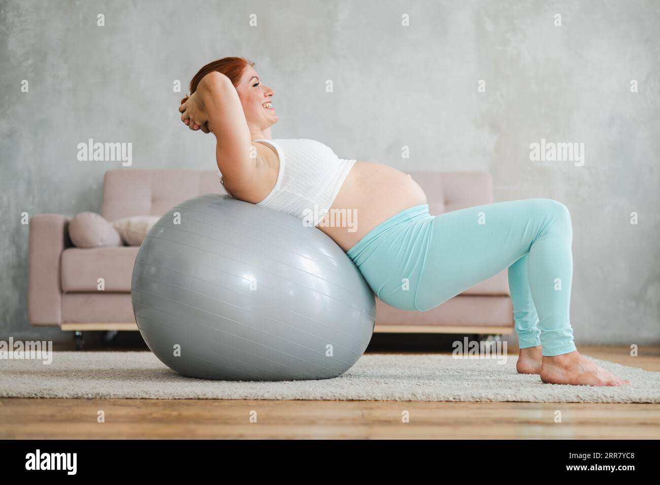 Pregnant red-haired woman doing fitball exercises at home Stock Photo ...