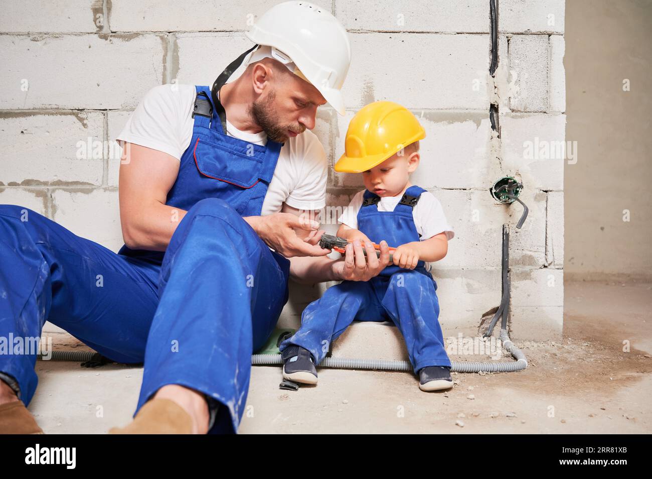 Male builder showing wire stripper cutter tool to child. Man and kid in ...