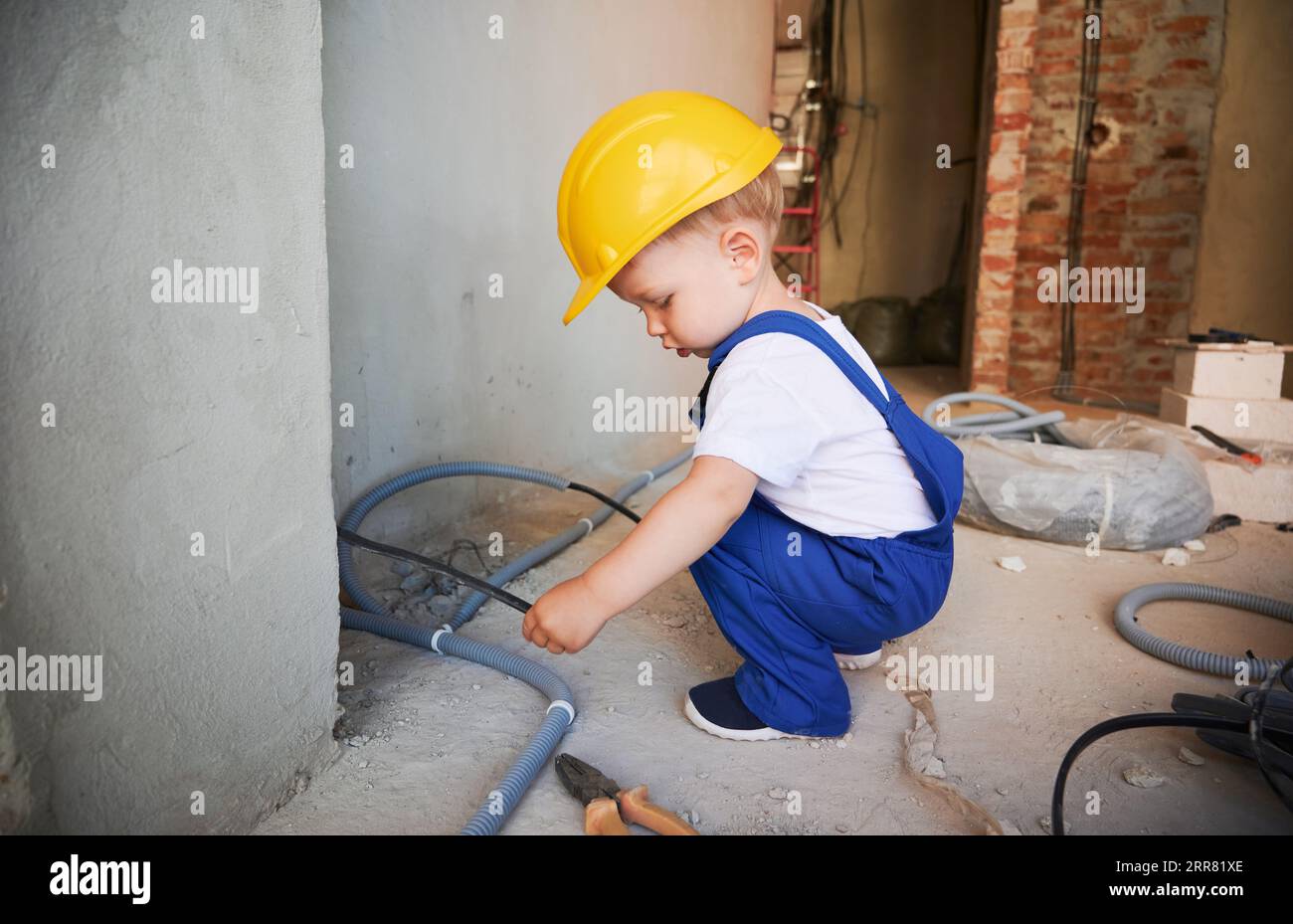 Little boy construction worker holding electrical wires in apartment ...
