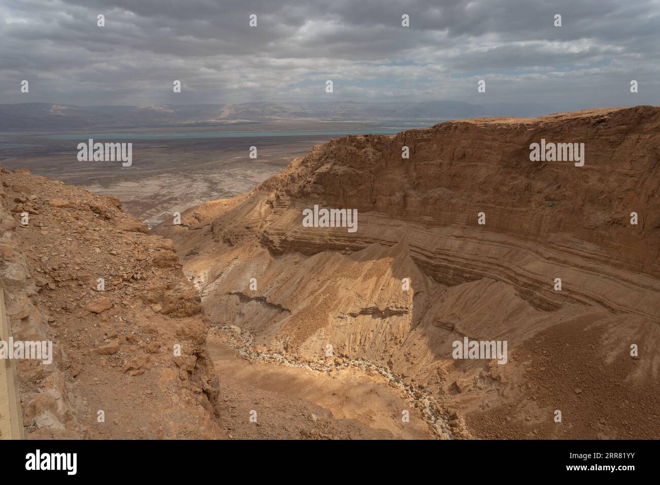 A winding, unpaved road is shown cutting through a barren desert ...