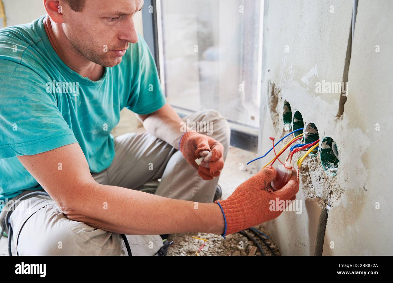 Close up of man in work gloves sitting by the wall and putting ...