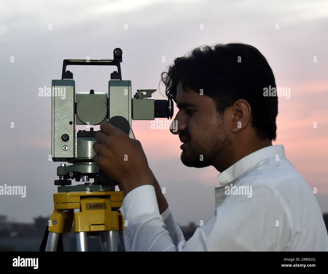 210413 -- PESHAWAR, April 13, 2021 -- A man observes the crescent moon ...