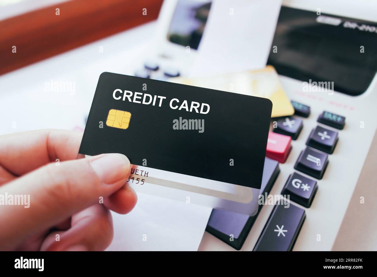 Hand holding credit card with printing calculator on table, black ...