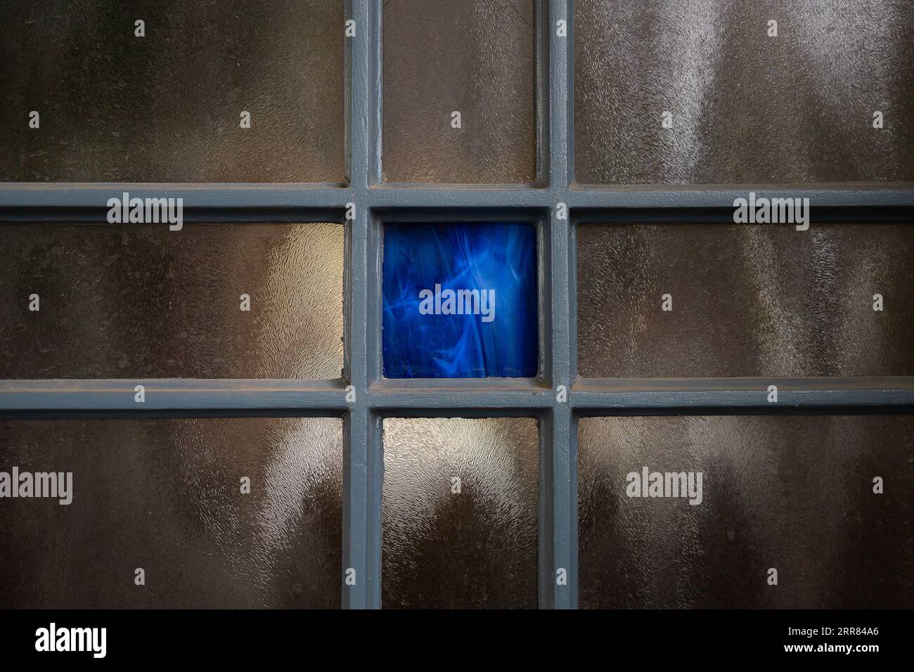 A blue-tinted glass window installed in a door, creating an ...