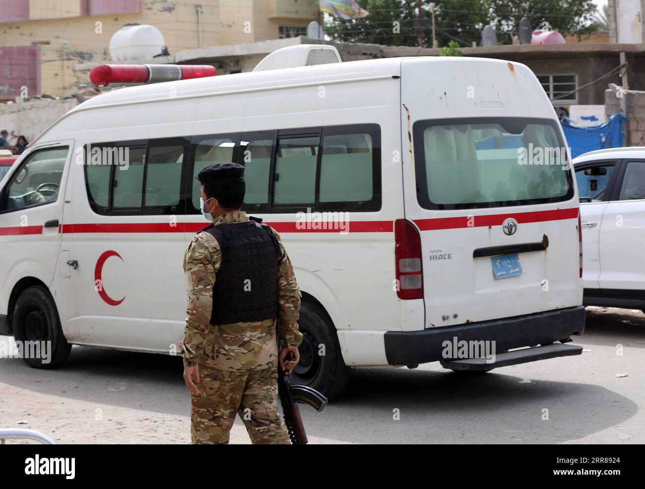 210425 -- BAGHDAD, April 25, 2021 -- A policeman passes by an ambulance ...