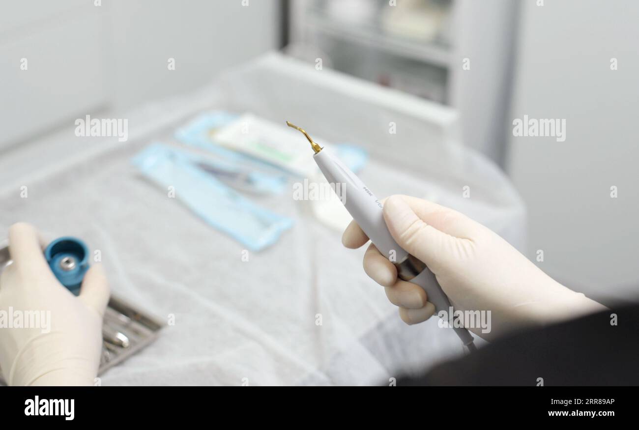 hands of doctor hold key nozzle and piezoelectric scaler removal of ...