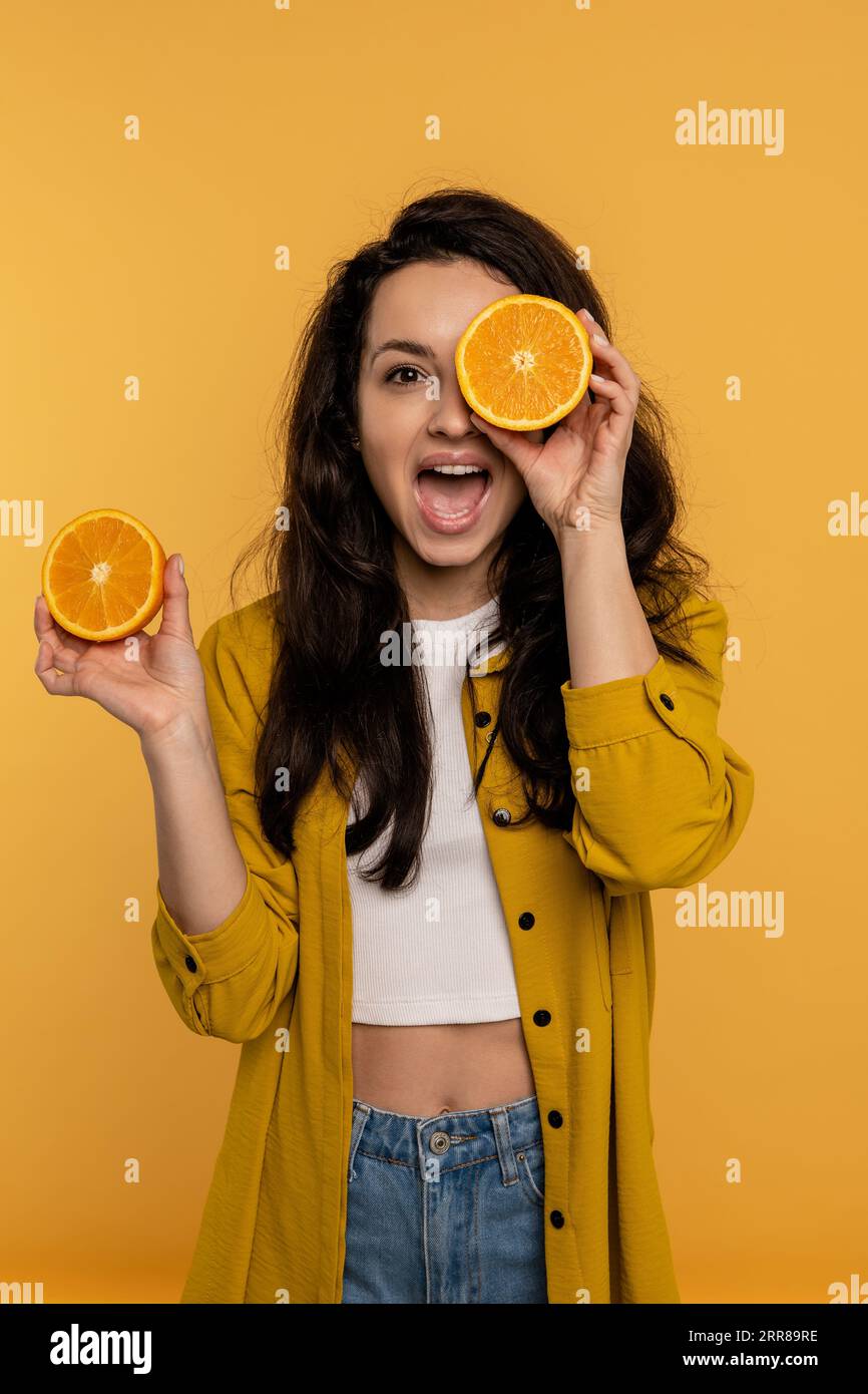 Playful brunette with halves of citrus fruit posing for the camera on ...