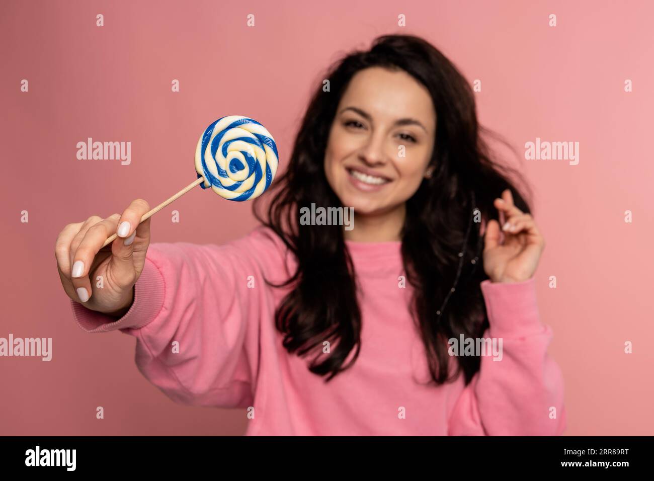 Joyful dark-haired young woman demonstrating her favorite hard candy ...