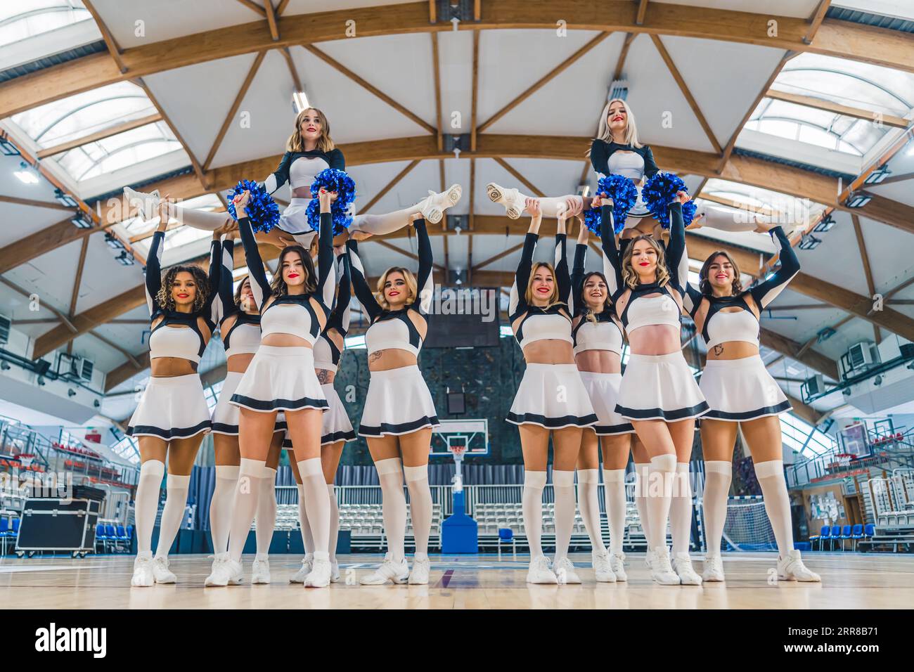 Cheerleaders doing a split while other girls holding them up in the air ...